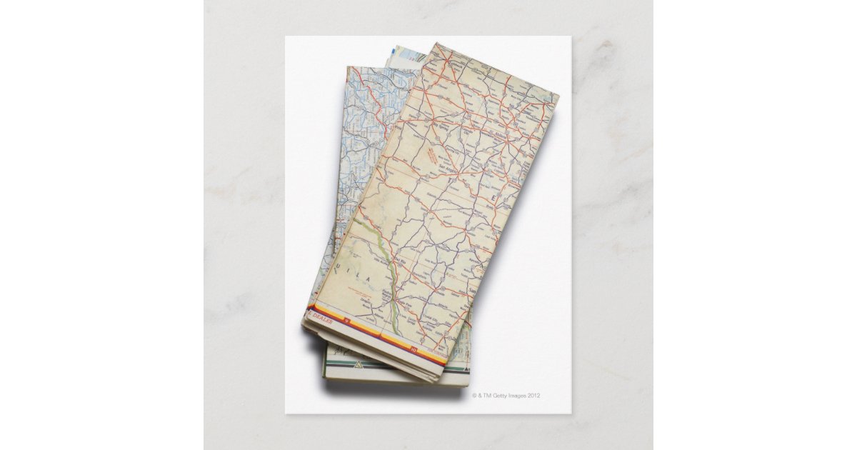 A stack of folded road maps on a white postcard | Zazzle